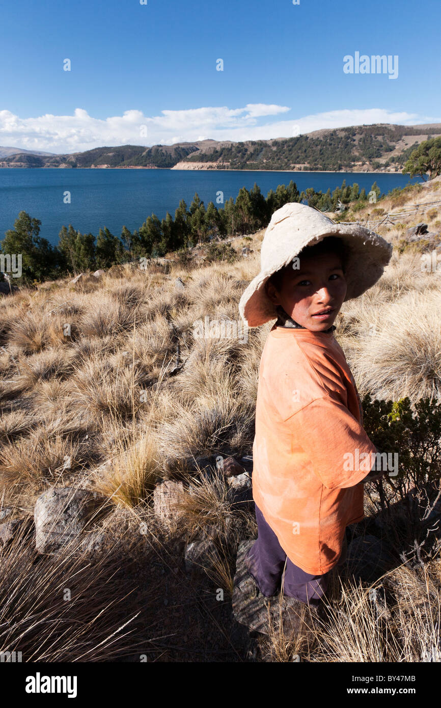 A young Peruvian farm boy on the island of Suasi with lake Titicaca in ...