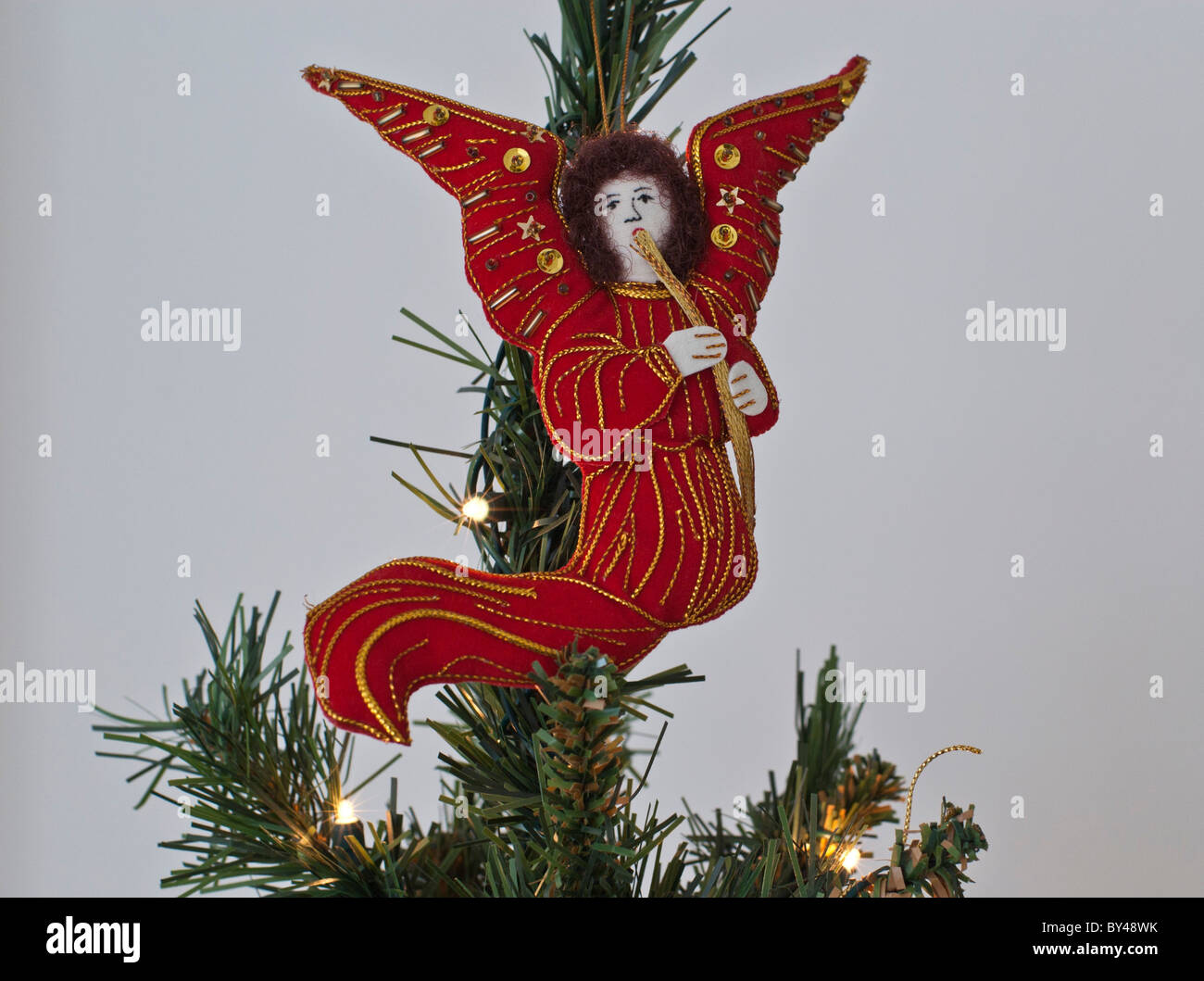 Red Angel on top of artificial Christmas Tree. Christmas decoration ...