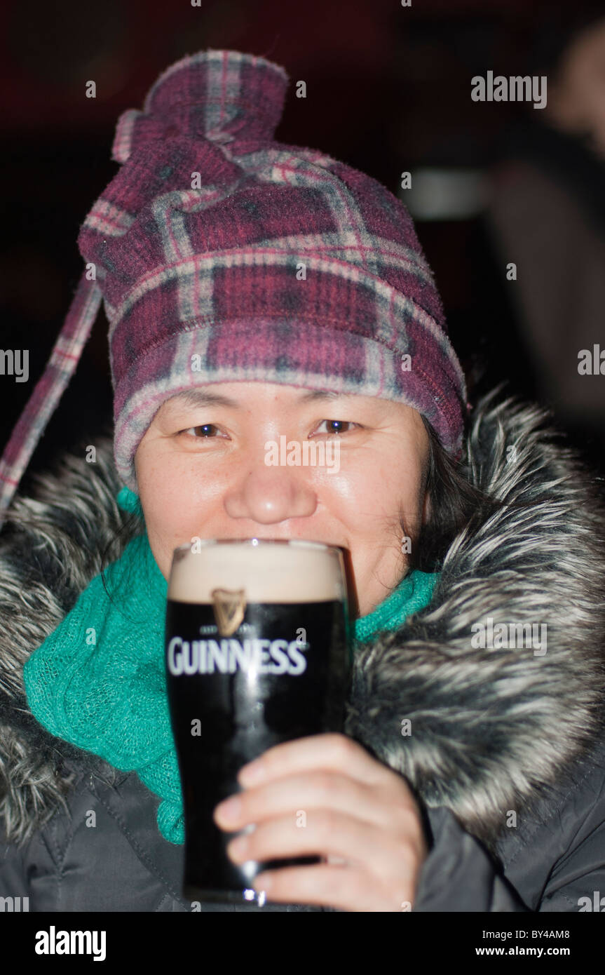 An Asian woman drinks a pint of Guinness in an Irish pub in Limerick ...