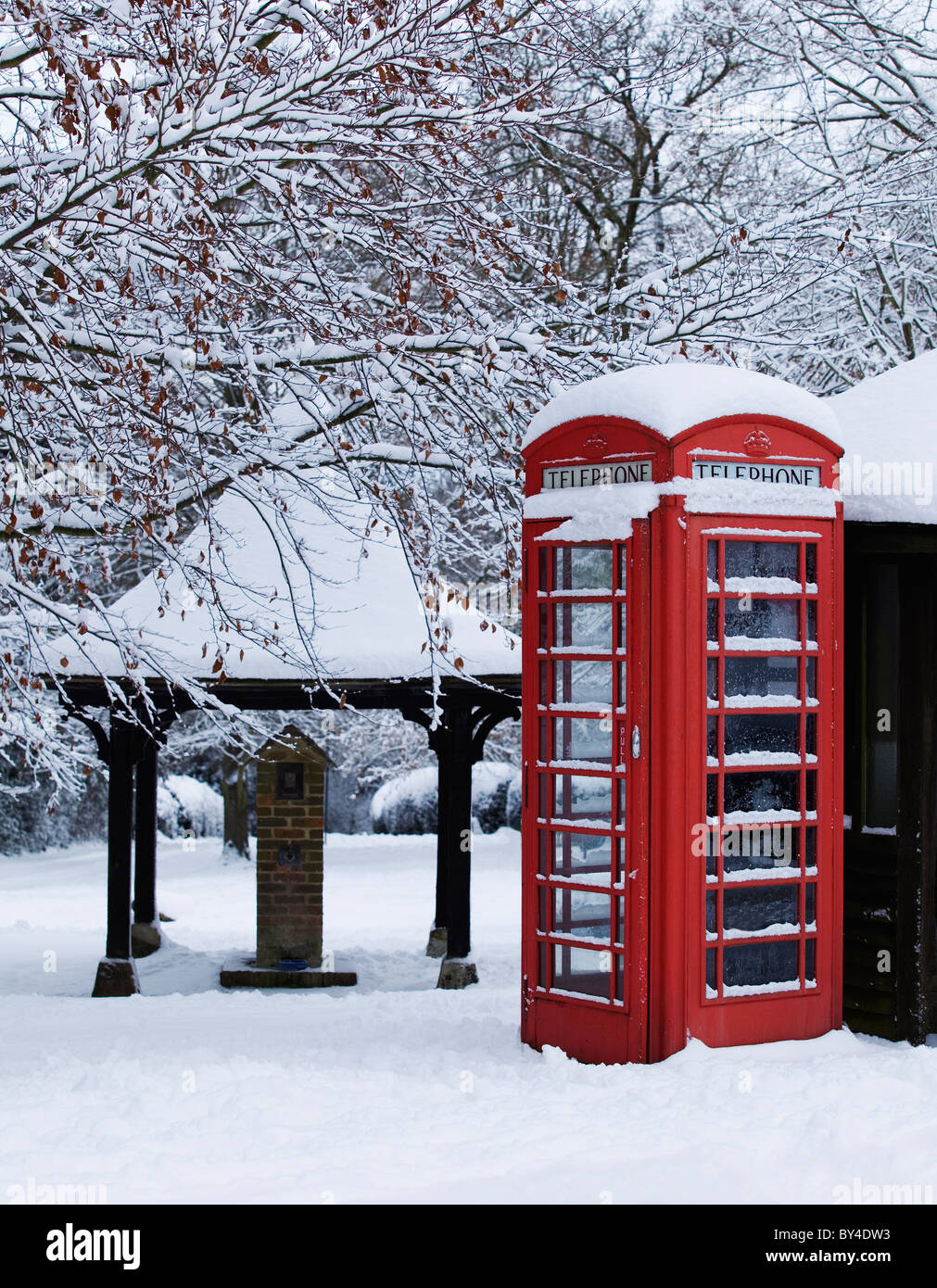 Red traditional telephone box with snow on a English village green ...