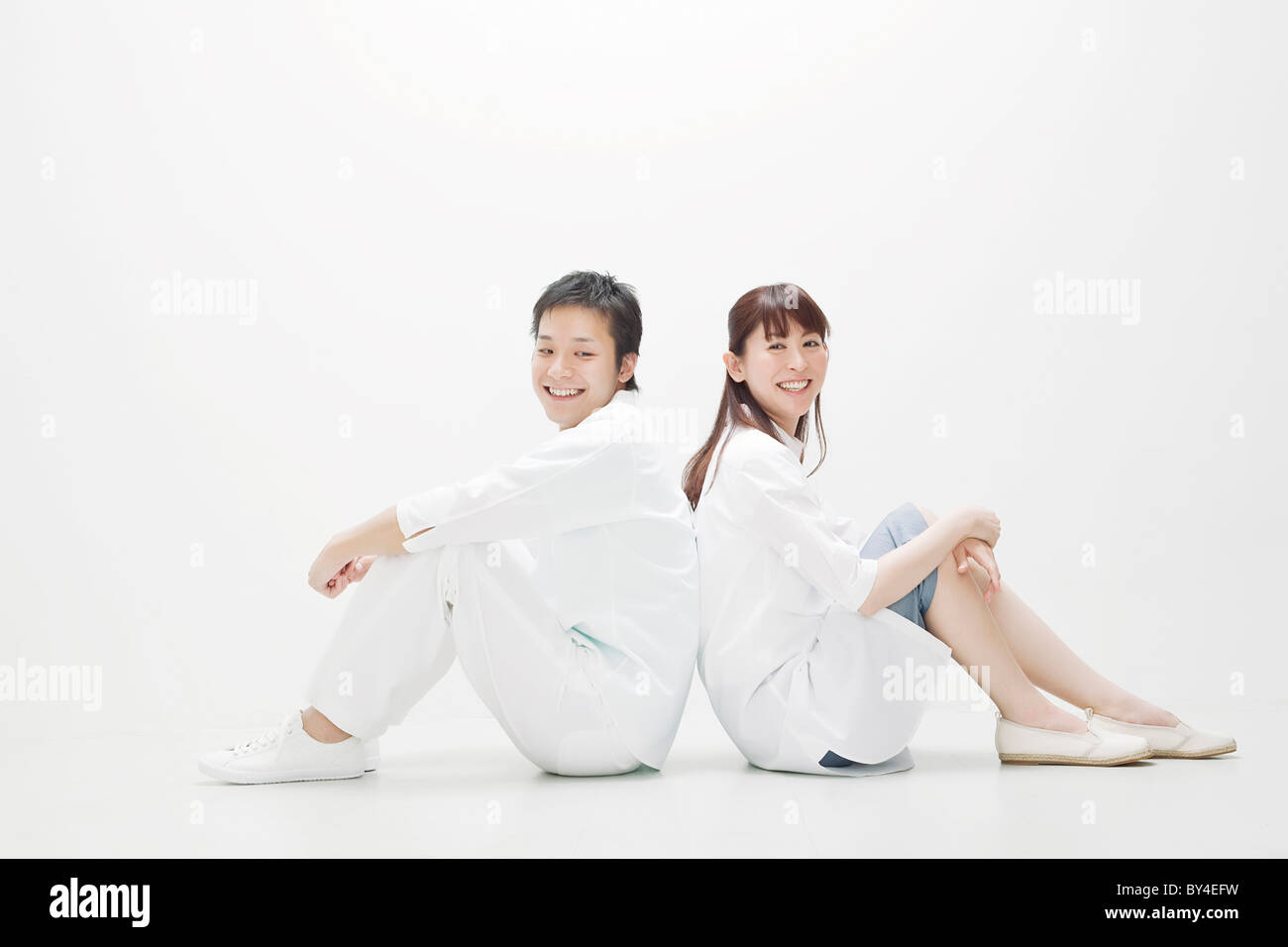 Young couple sitting back to back Stock Photo - Alamy