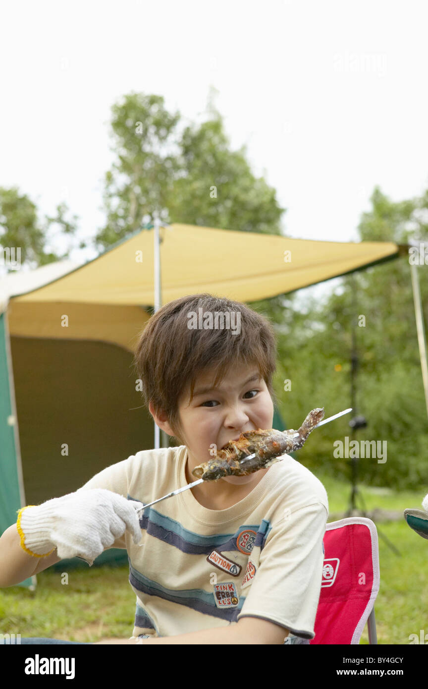 Boy Eating Barbecued Fish From Skewer Stock Photo - Alamy