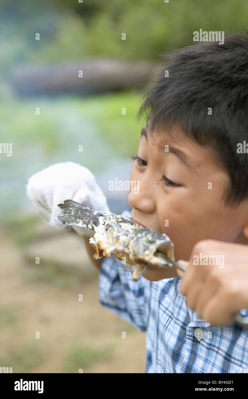 Boy Eating Barbecued Fish Stock Photo - Alamy