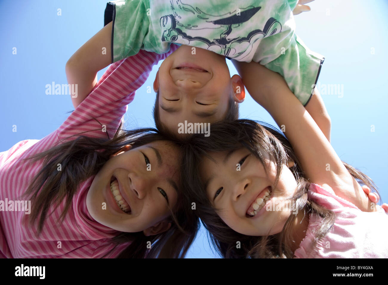 Three Children Huddling Stock Photo - Alamy