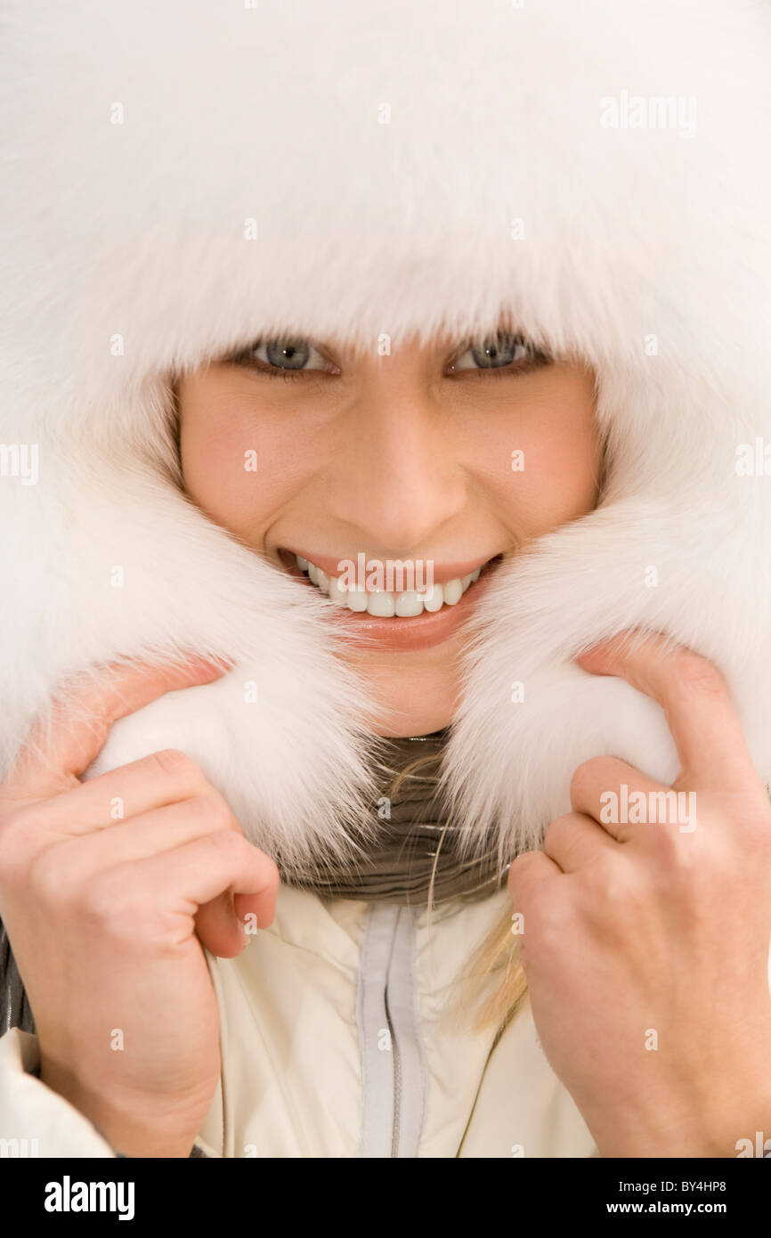 Portrait of beautiful female wearing pure white fur cap and smiling ...