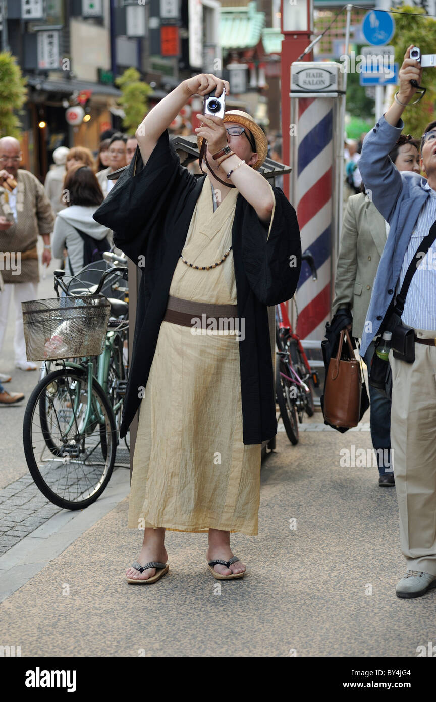 Traditionally dressed Japanese man taking a picture at Sanja Matsuri ...