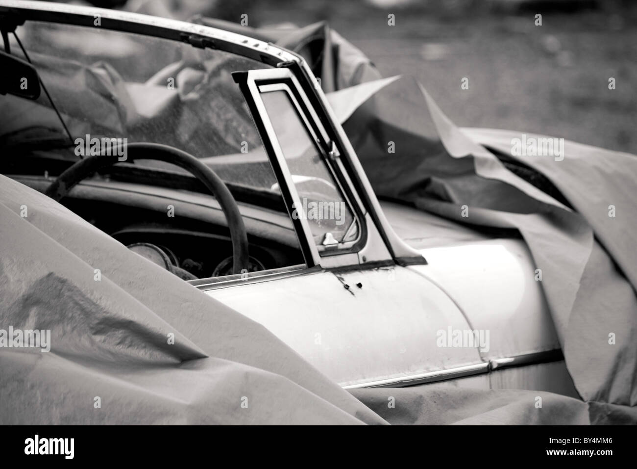 A covered up white convertible classic MG car ready to be fixed, done ...