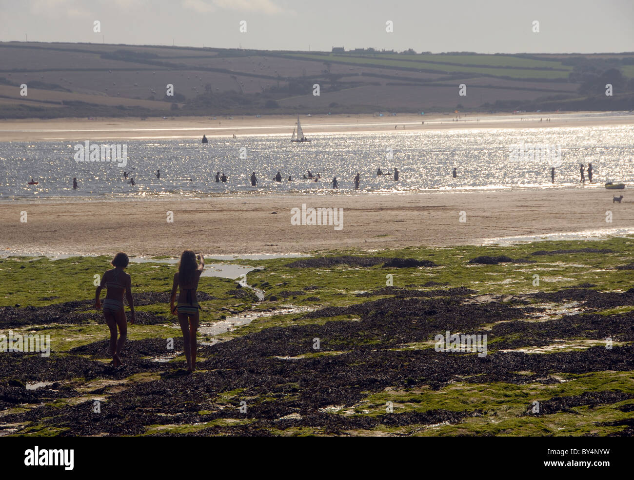 Girls on the rocks and swimmers in the sea, Daymer Bay, North Cornwall ...