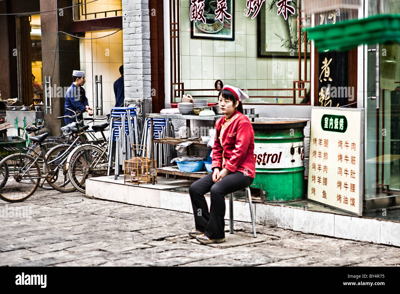CHINA, XIAN: Young Chinese restaurant worker waiting on the sidewalk ...