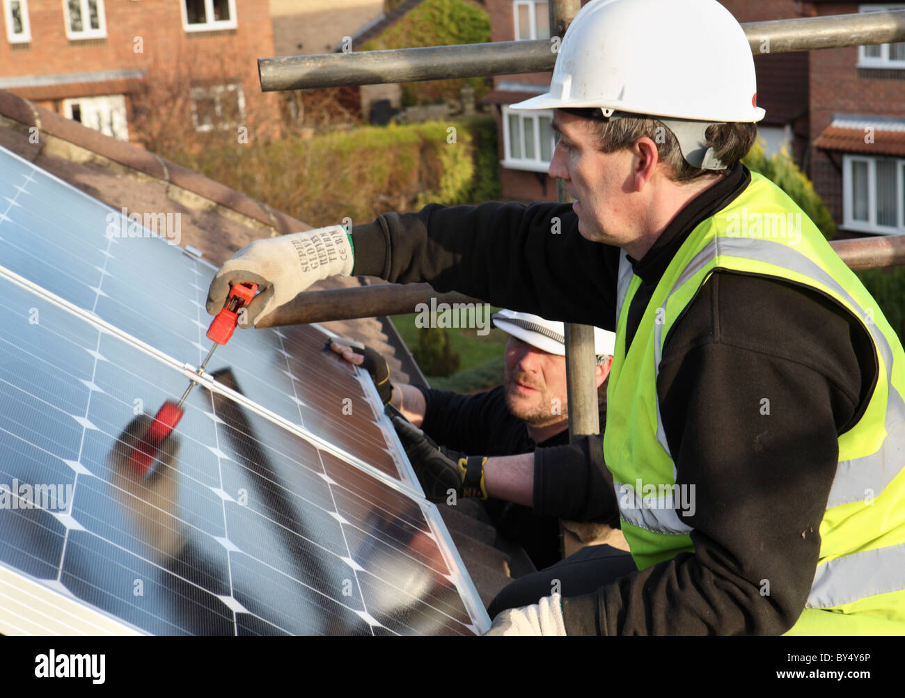 Installing photo voltaic solar panels onto the roof of a domestic house ...