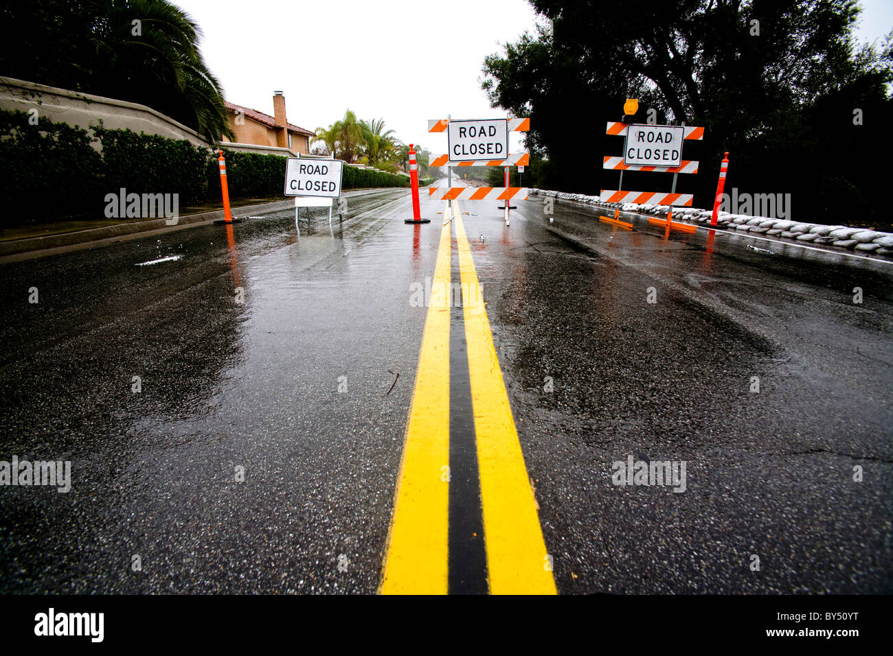 Three stop signs warn traffic away from a washed out road following ...