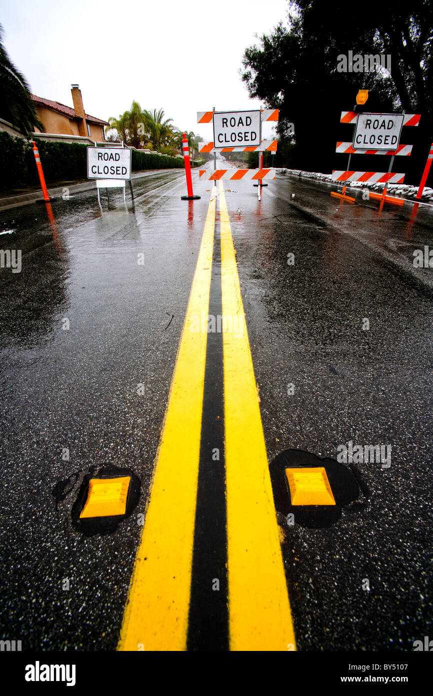 Three stop signs warn traffic away from a washed out road following ...