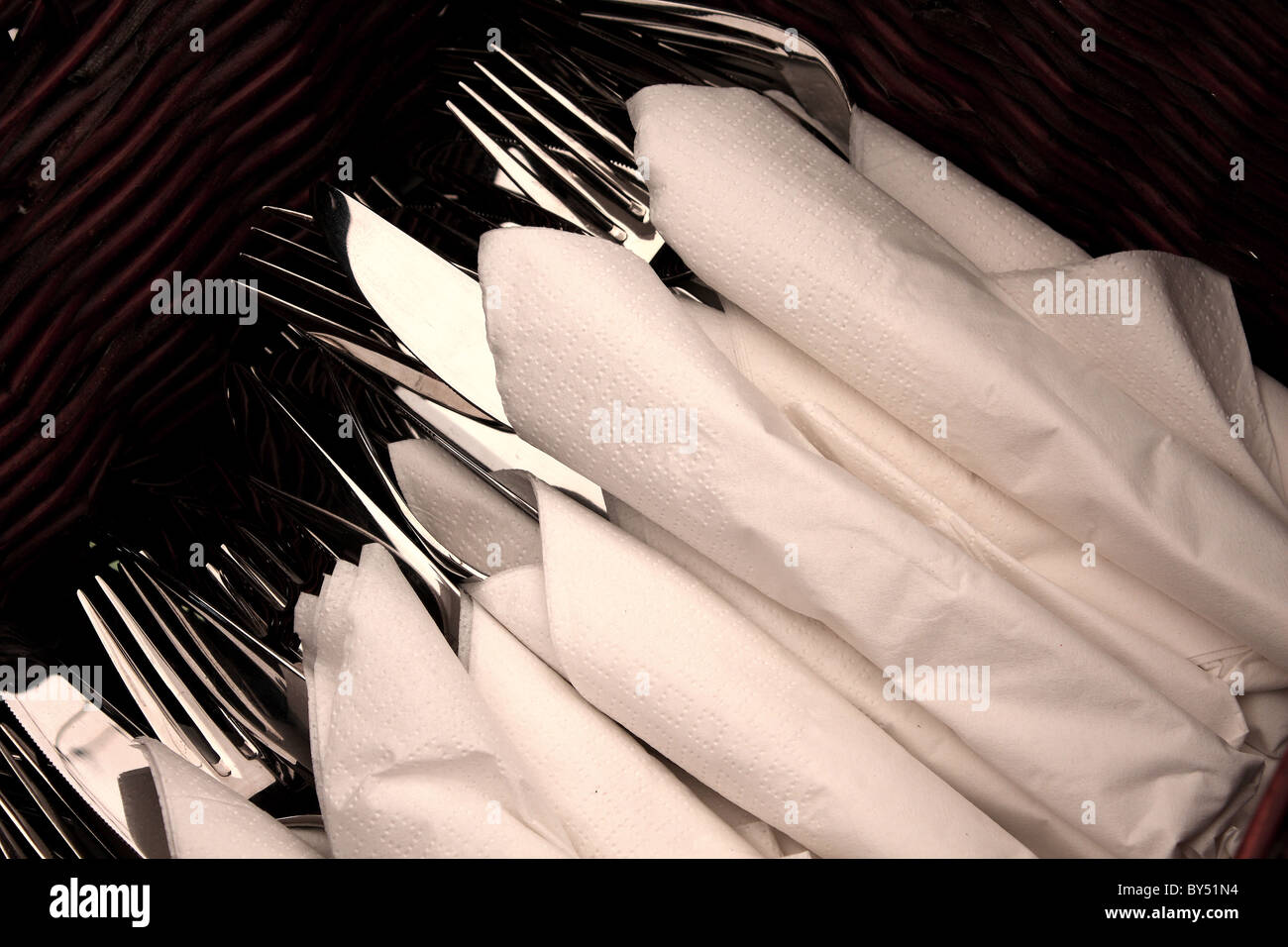 A collection of knives, forks and spoons wrapped up in white serviettes ...