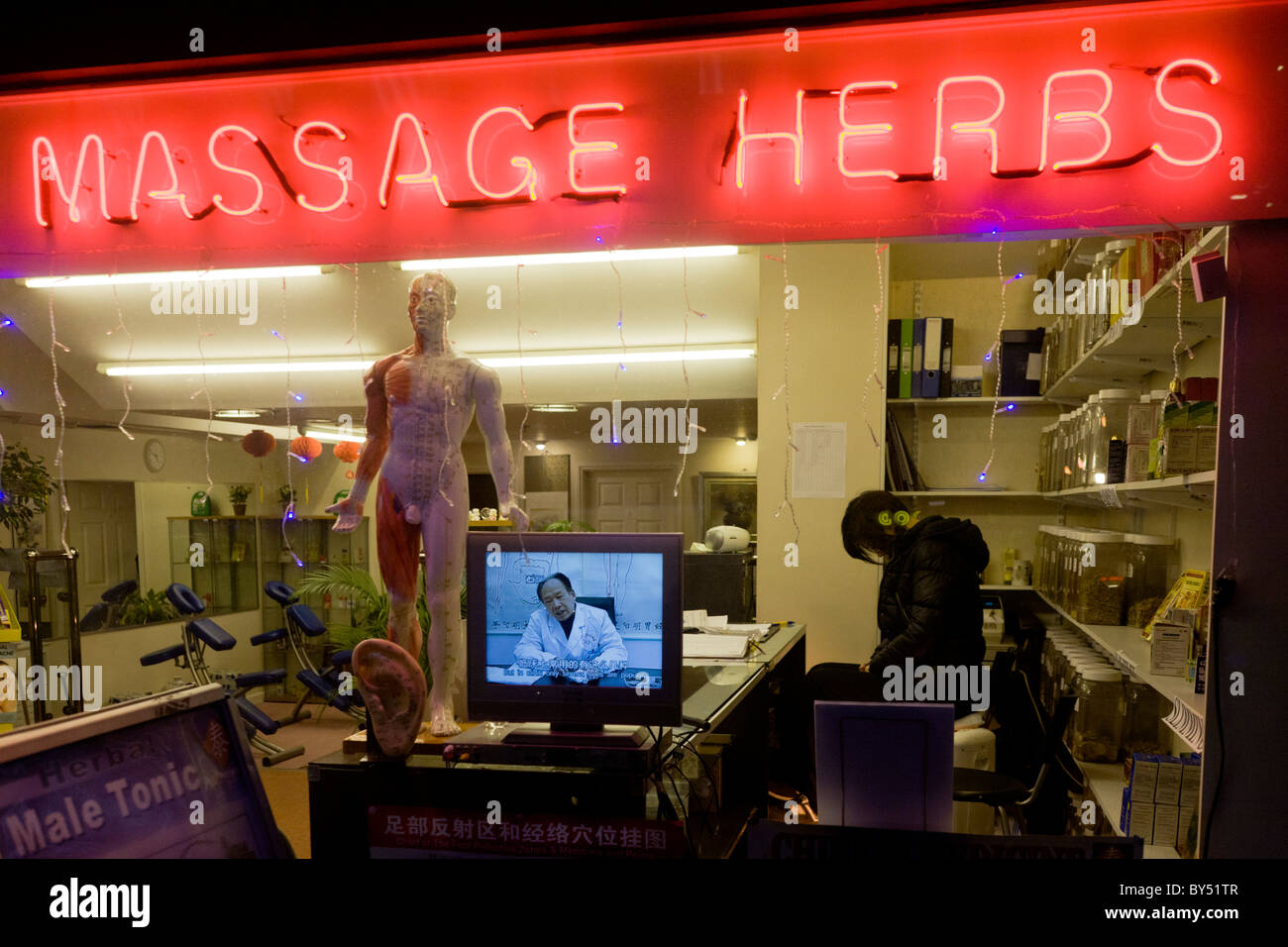 Tired assistant with Doctor on TV screen at a traditional Chinese ...