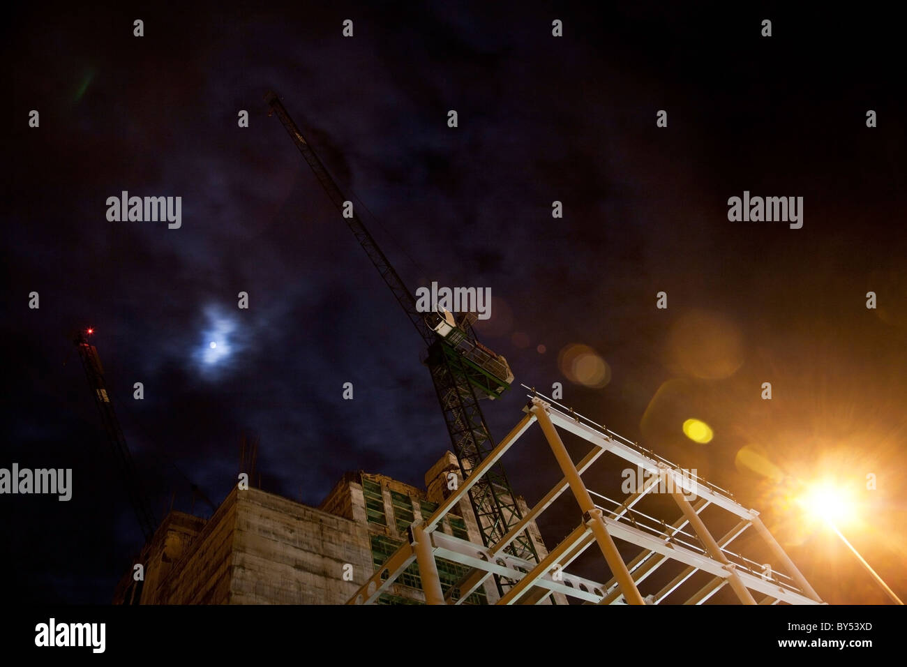 Construction site, tall cranes, full moon and street lights Stock Photo ...