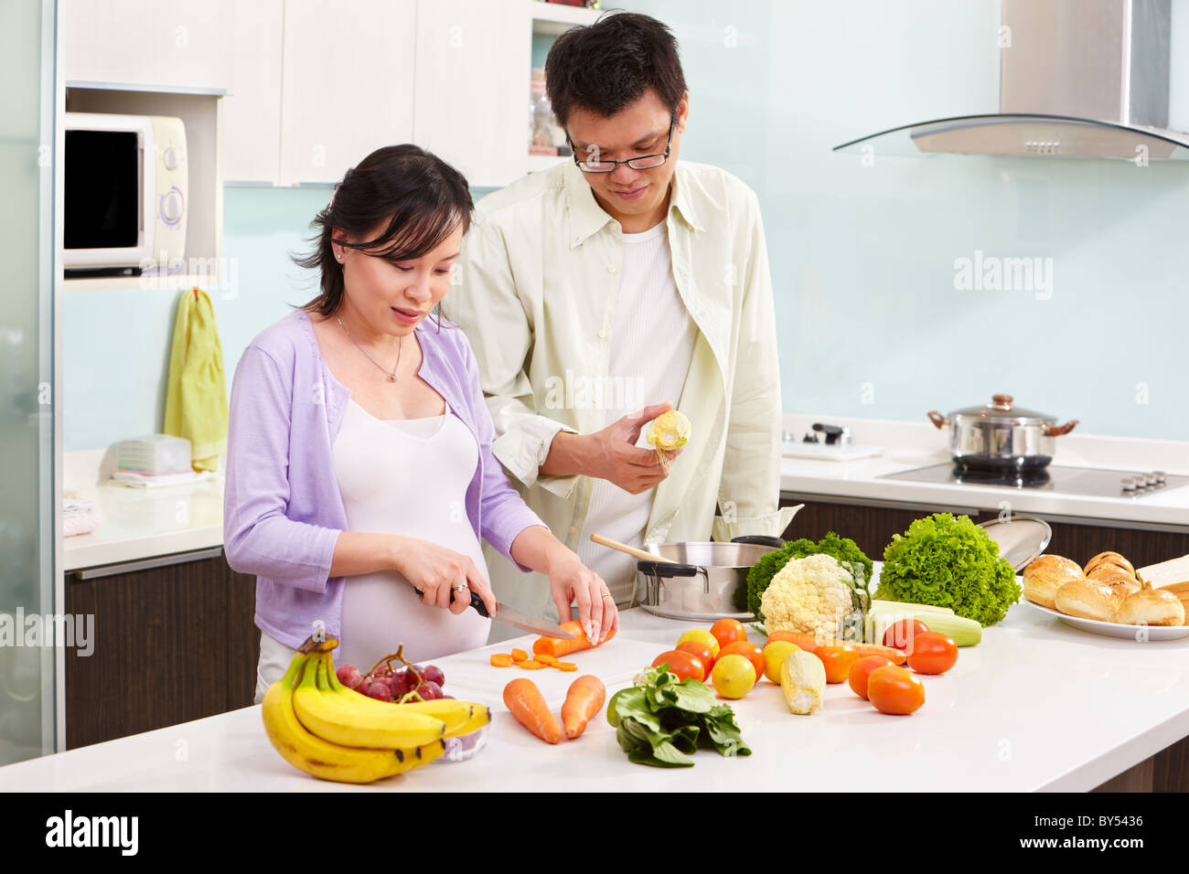 Asian couple ( pregnant wife ) busy preparing food in kitchen Stock ...