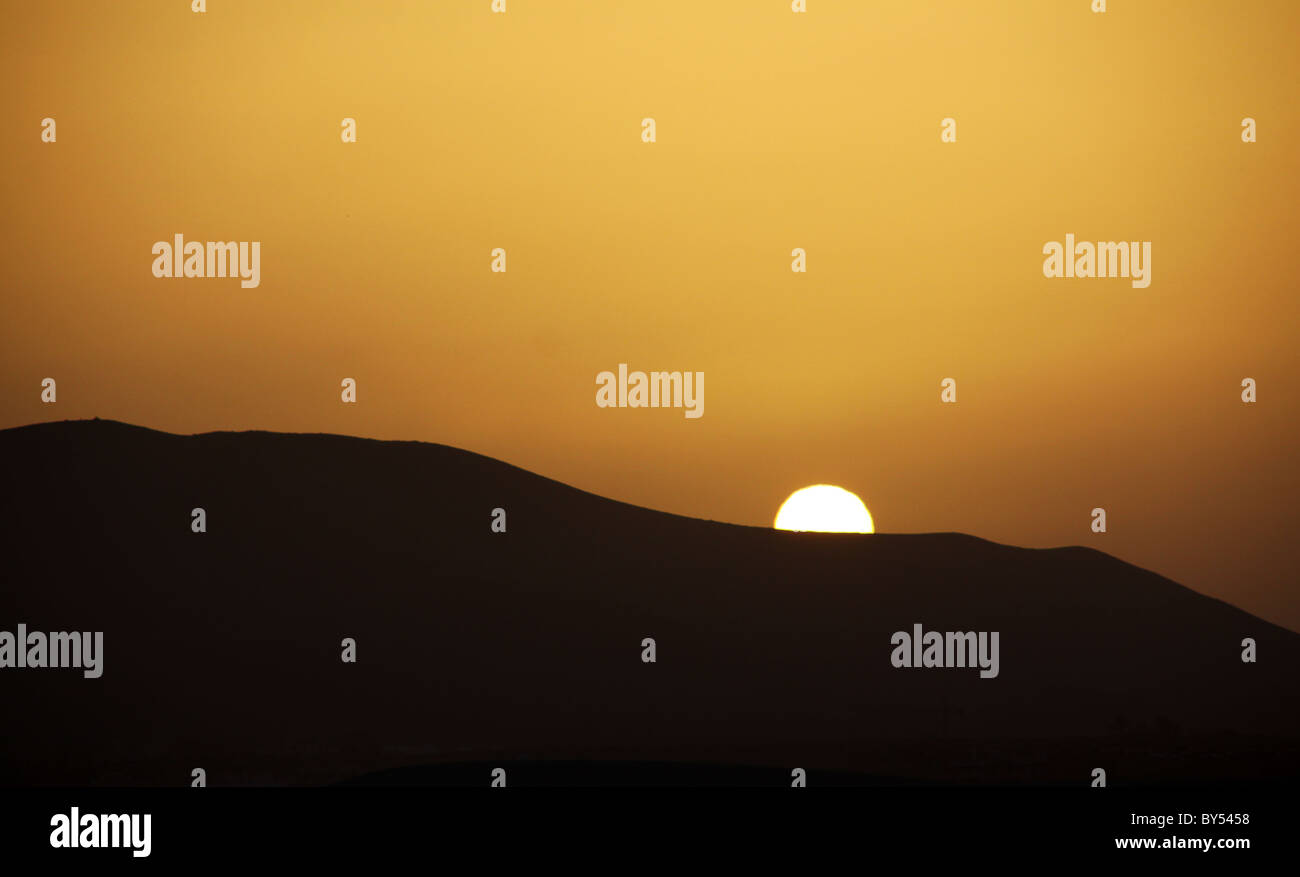 Setting sun over ridgeline of hill Stock Photo - Alamy