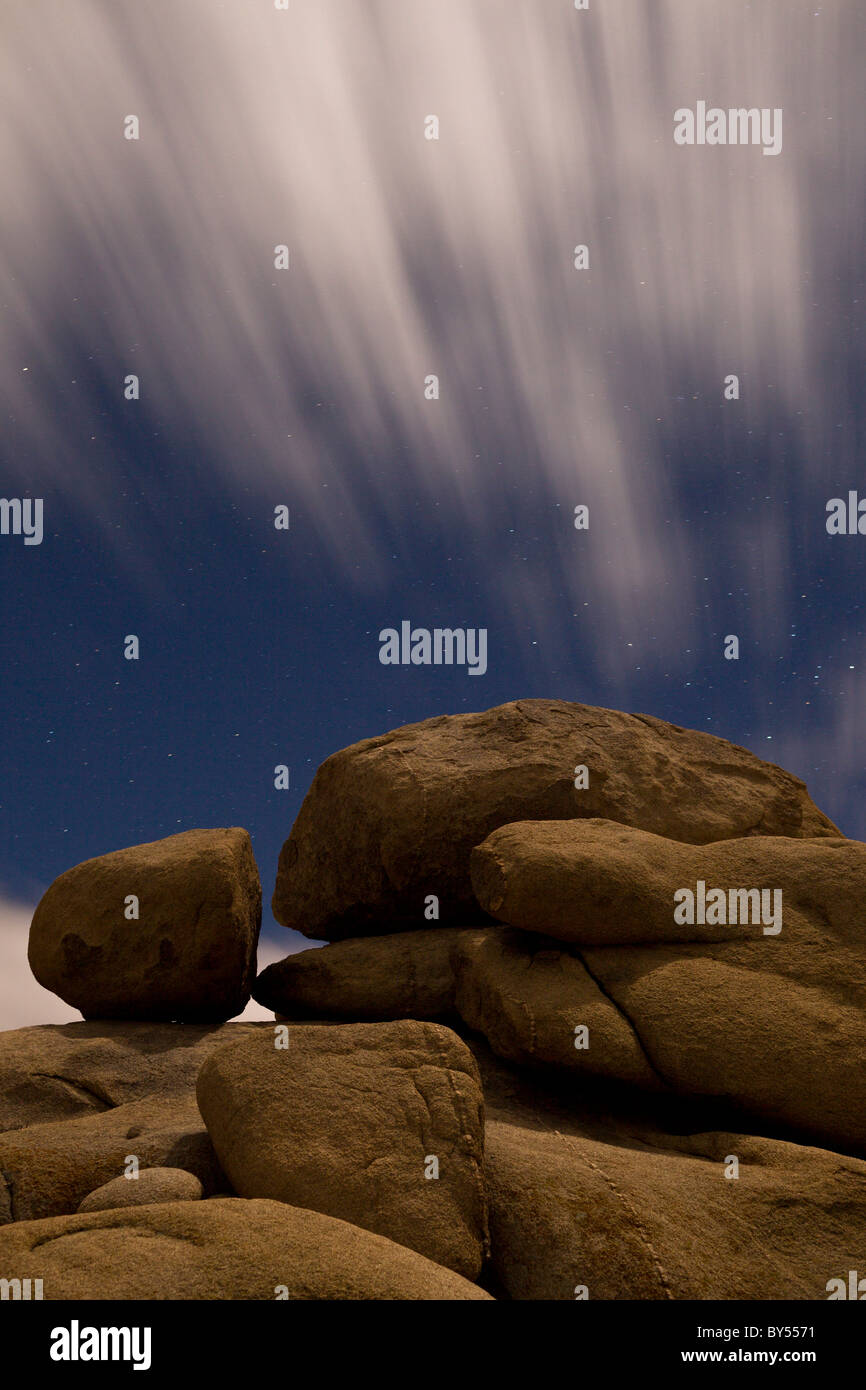 Clouds loom over a moonlit landscape of granite boulders at Joshua Tree ...