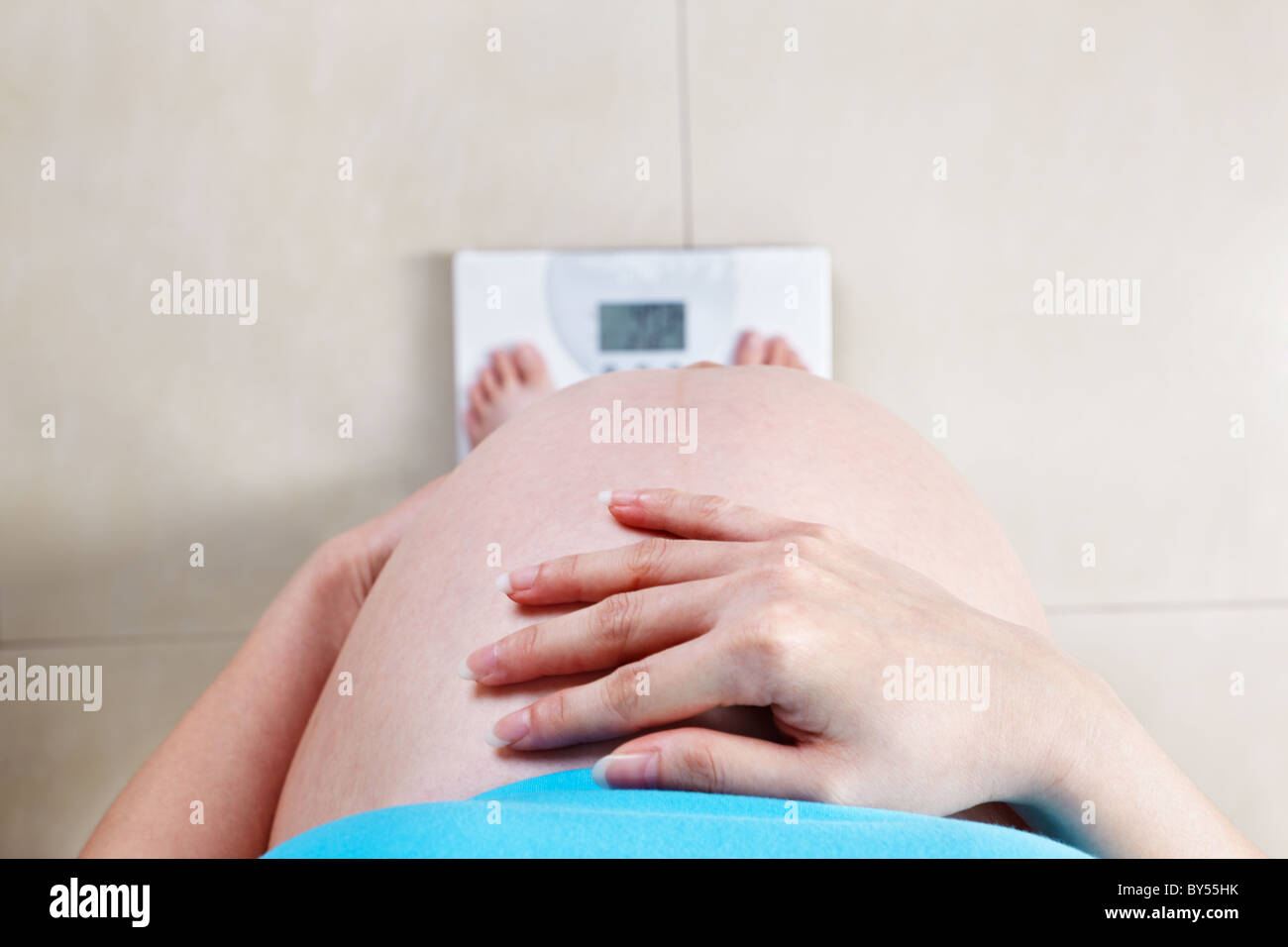 Pregnant lady measuring her weight, taken from high angle Stock Photo ...