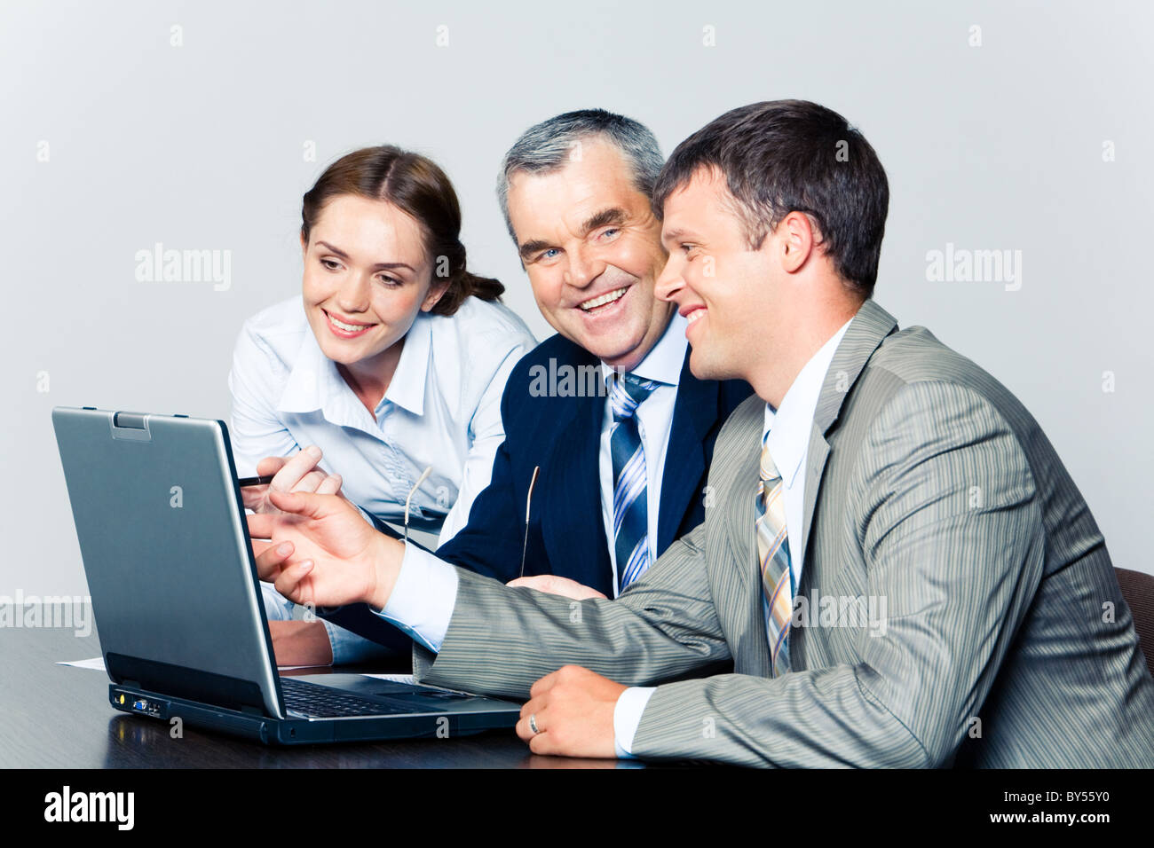 Portrait of smiling people discussing a computer work together at ...