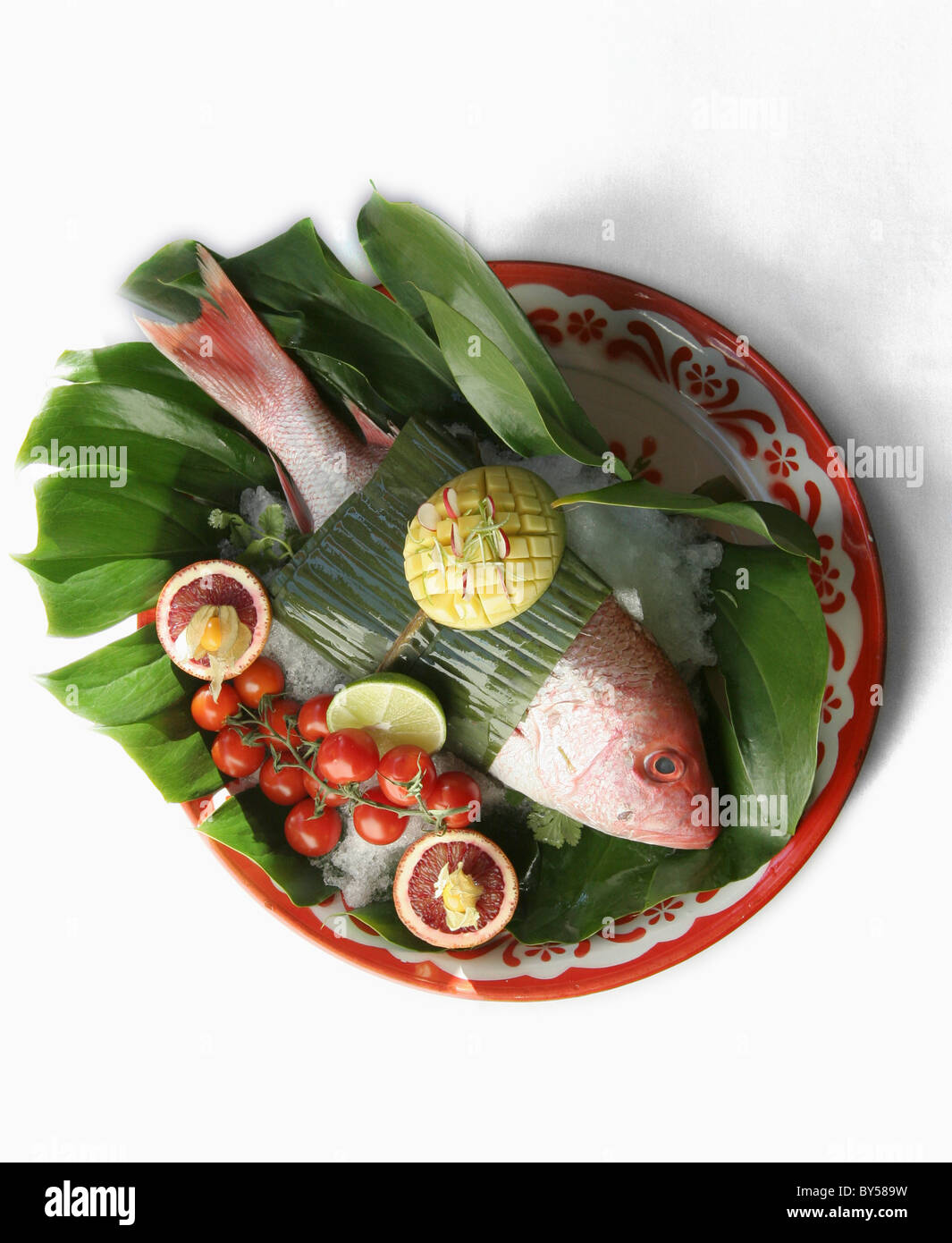 Red snapper wrapped in a banana leaf with garnish Stock Photo - Alamy