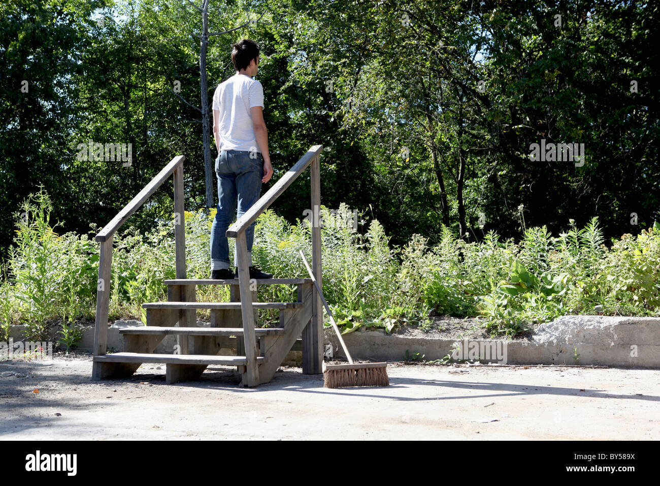 A man standing at the top of a staircase going nowhere, rear view ...