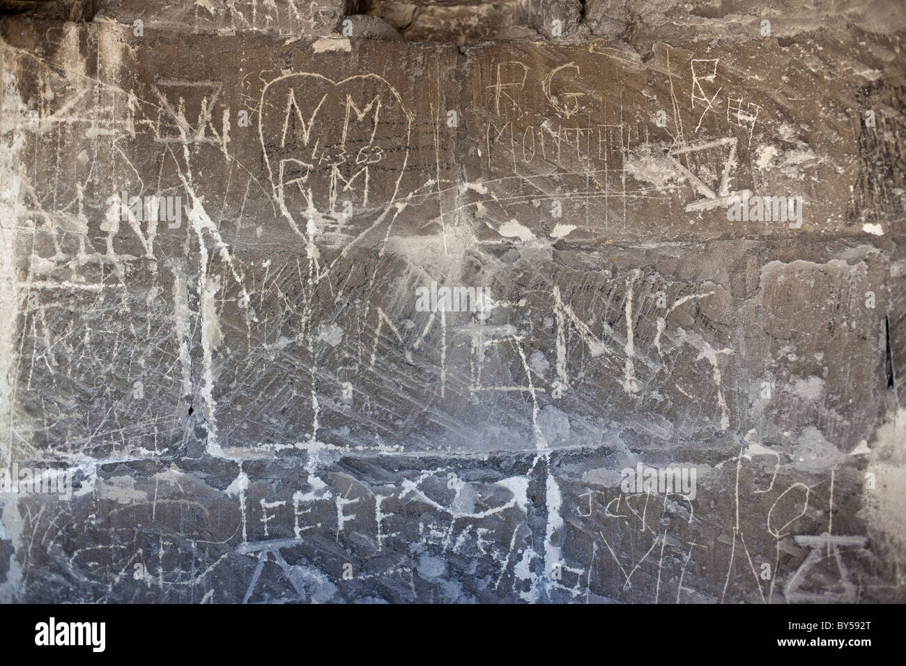 Handwritten graffiti etched into a stone wall Stock Photo - Alamy