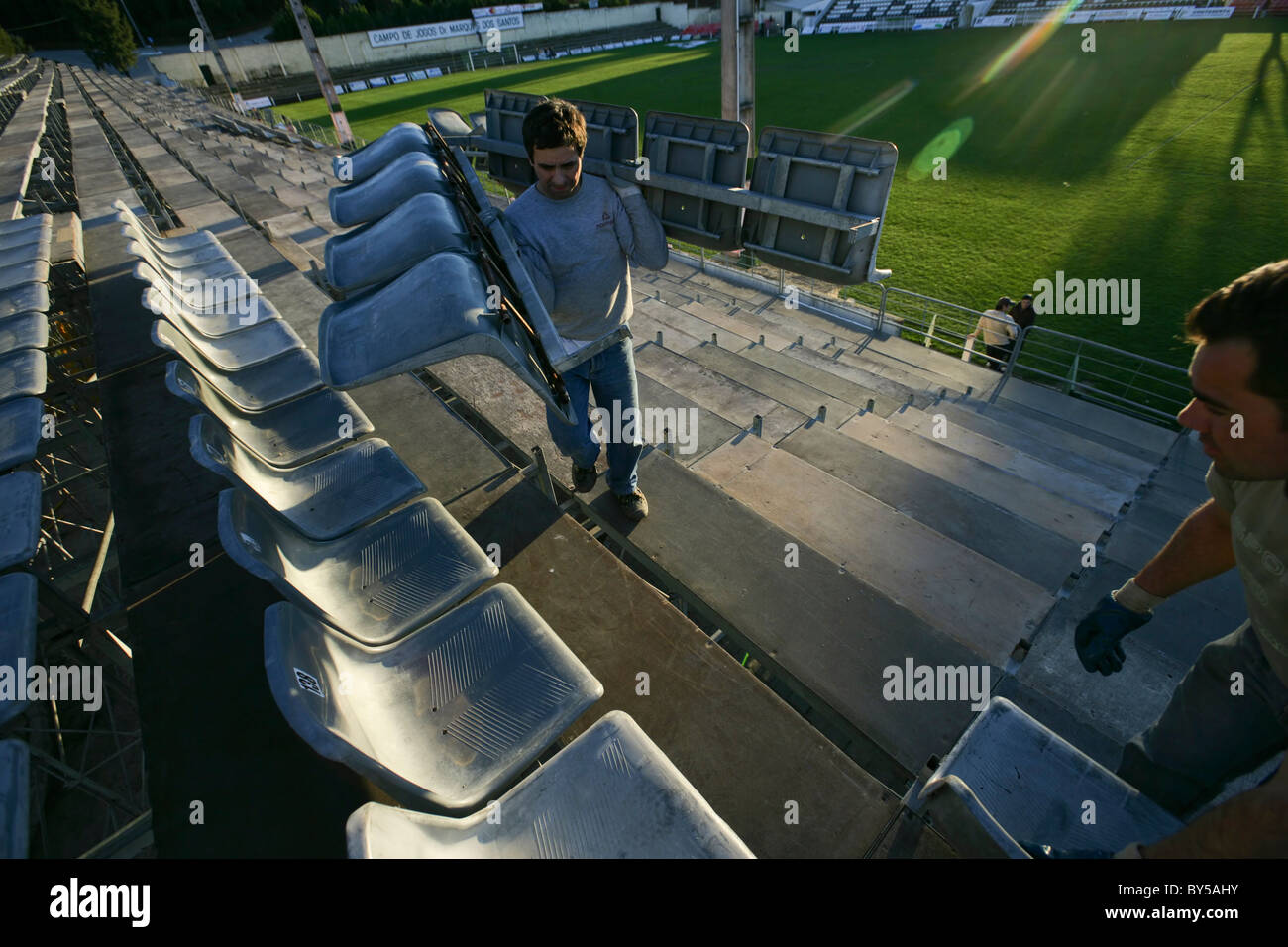 Two men installing seats at a football stadium Stock Photo - Alamy