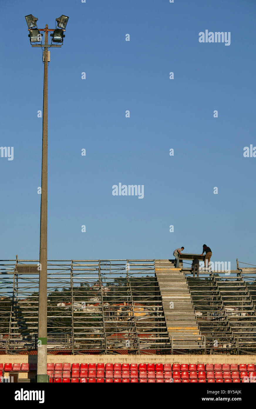 Three men installing seats at a football stadium Stock Photo - Alamy
