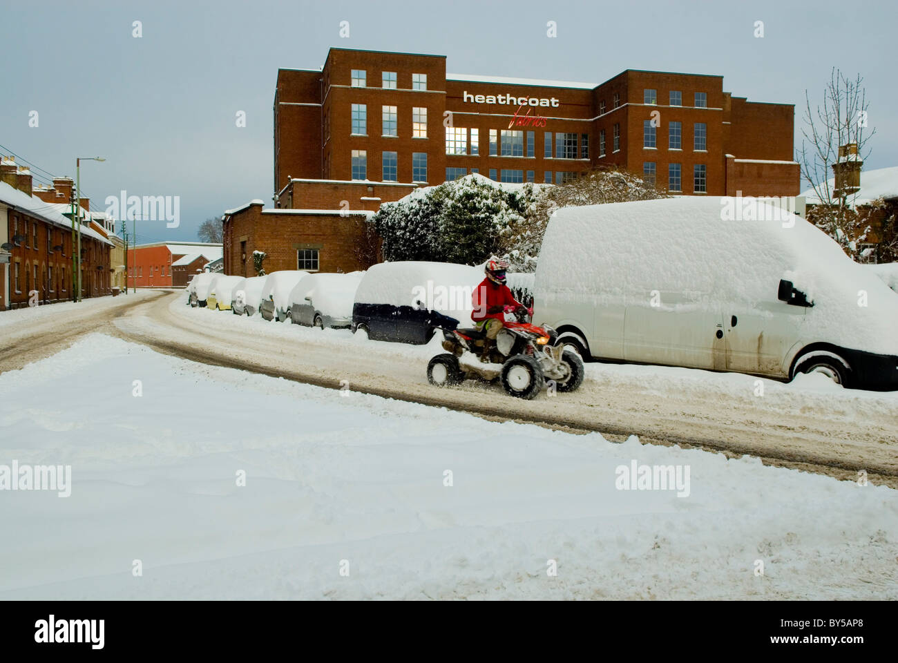 Quad bike and rider riding through a snow covered street Stock Photo ...