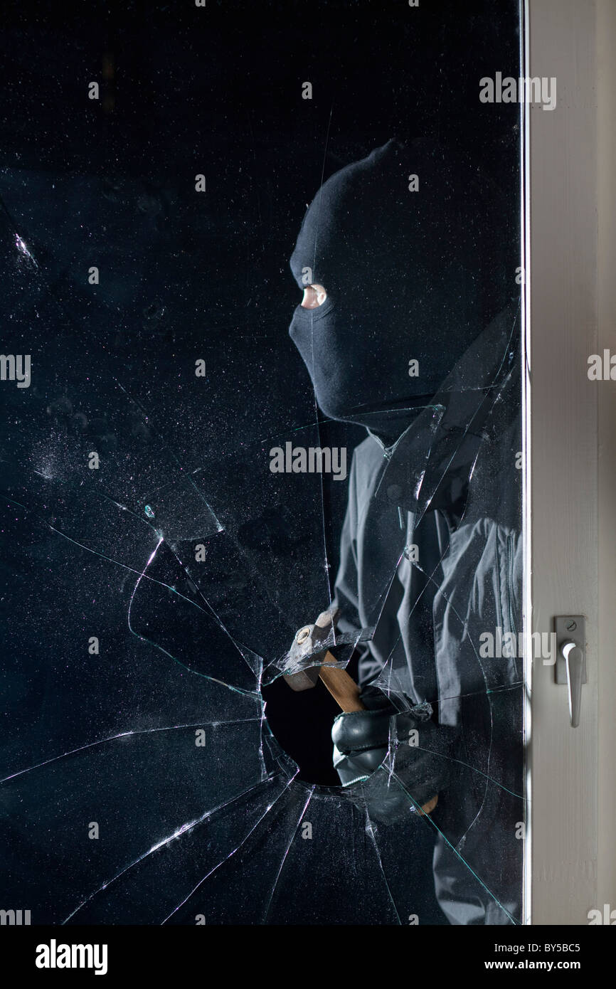A criminal breaking into a window with a hammer Stock Photo - Alamy