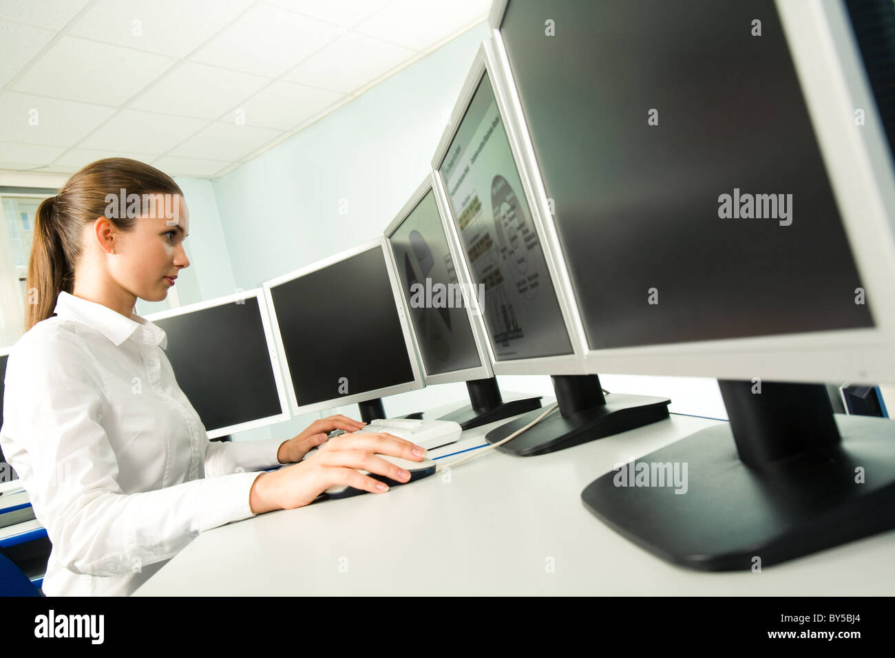 Photo of smart girl sitting by computer and looking at its monitor in ...