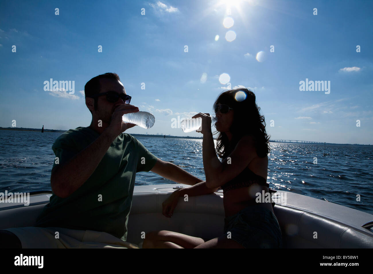 A couple out on their boat drinking bottled water Stock Photo - Alamy