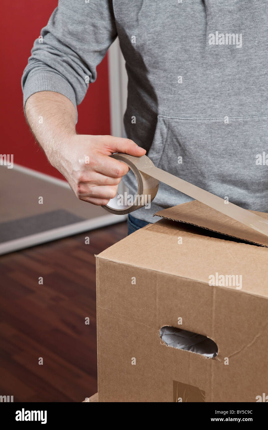 A man taping a moving box shut, midsection Stock Photo - Alamy