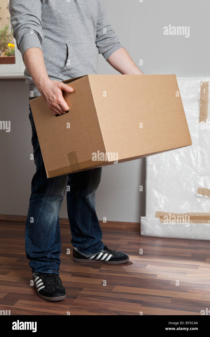 A man carrying a moving box, neck down Stock Photo - Alamy