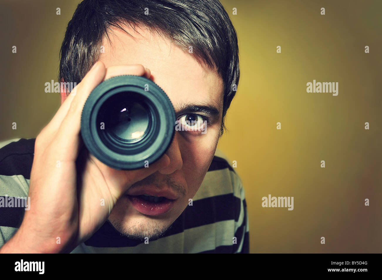 Handsome young man holding camera lens like it was spyglass Stock Photo ...