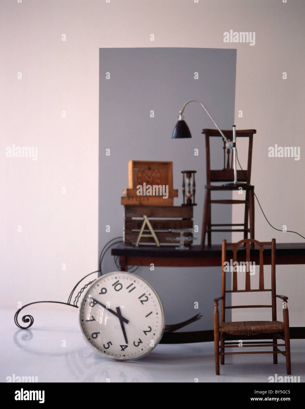 Circular Clock Face With Traditional Wooden Chairs And Angle Poise Lamp