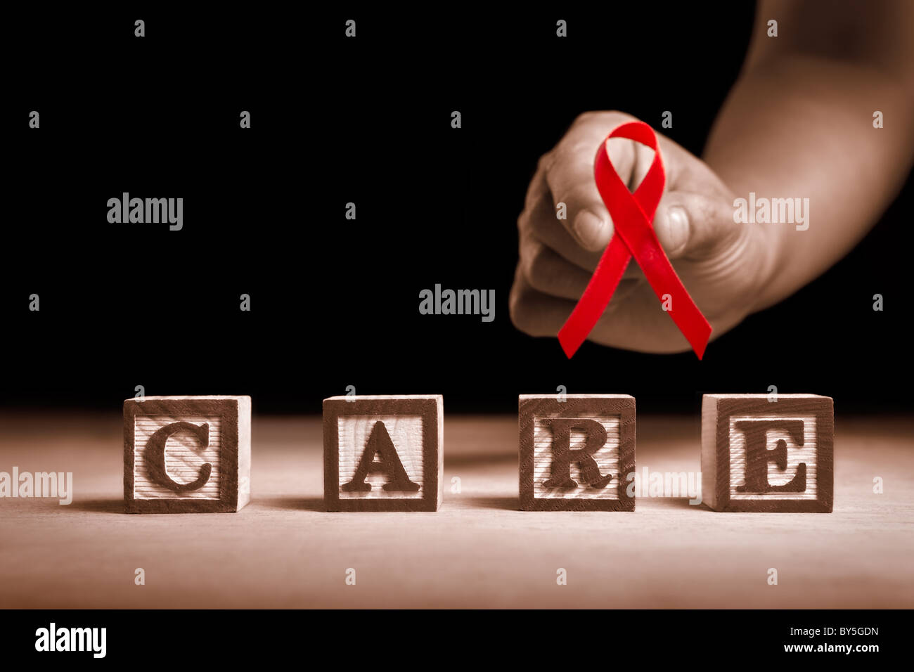 Word 'Care' from wooden block with hand holding red ribbon on dark ...