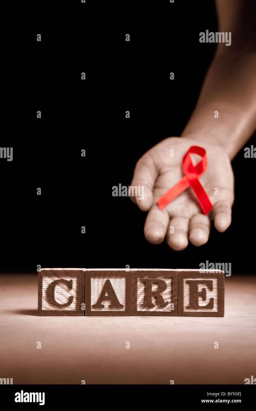 Word 'Care' from wooden block with hand holding red ribbon on dark ...