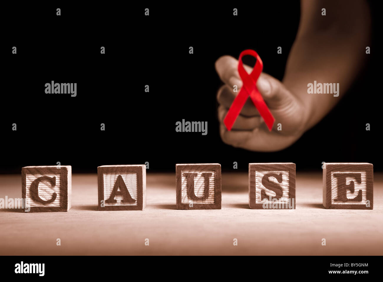 Word 'Cause' from wooden block with hand holding red ribbon on dark ...