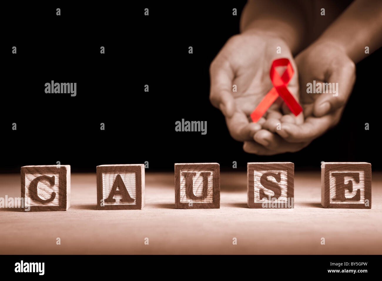 Word 'Cause' from wooden block with hand holding red ribbon on dark ...