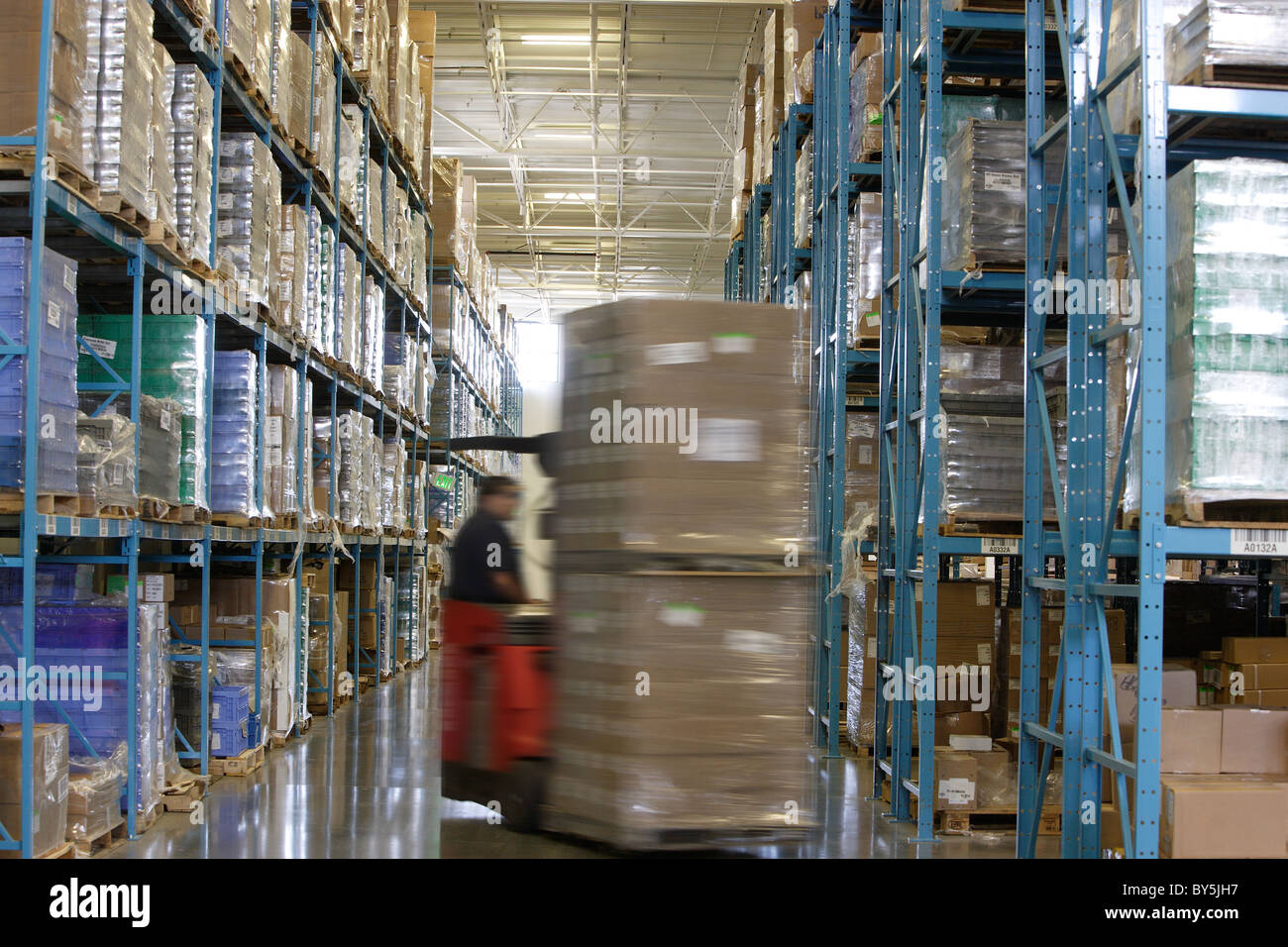 A forklift moving pallets of goods in a large warehouse Stock Photo - Alamy