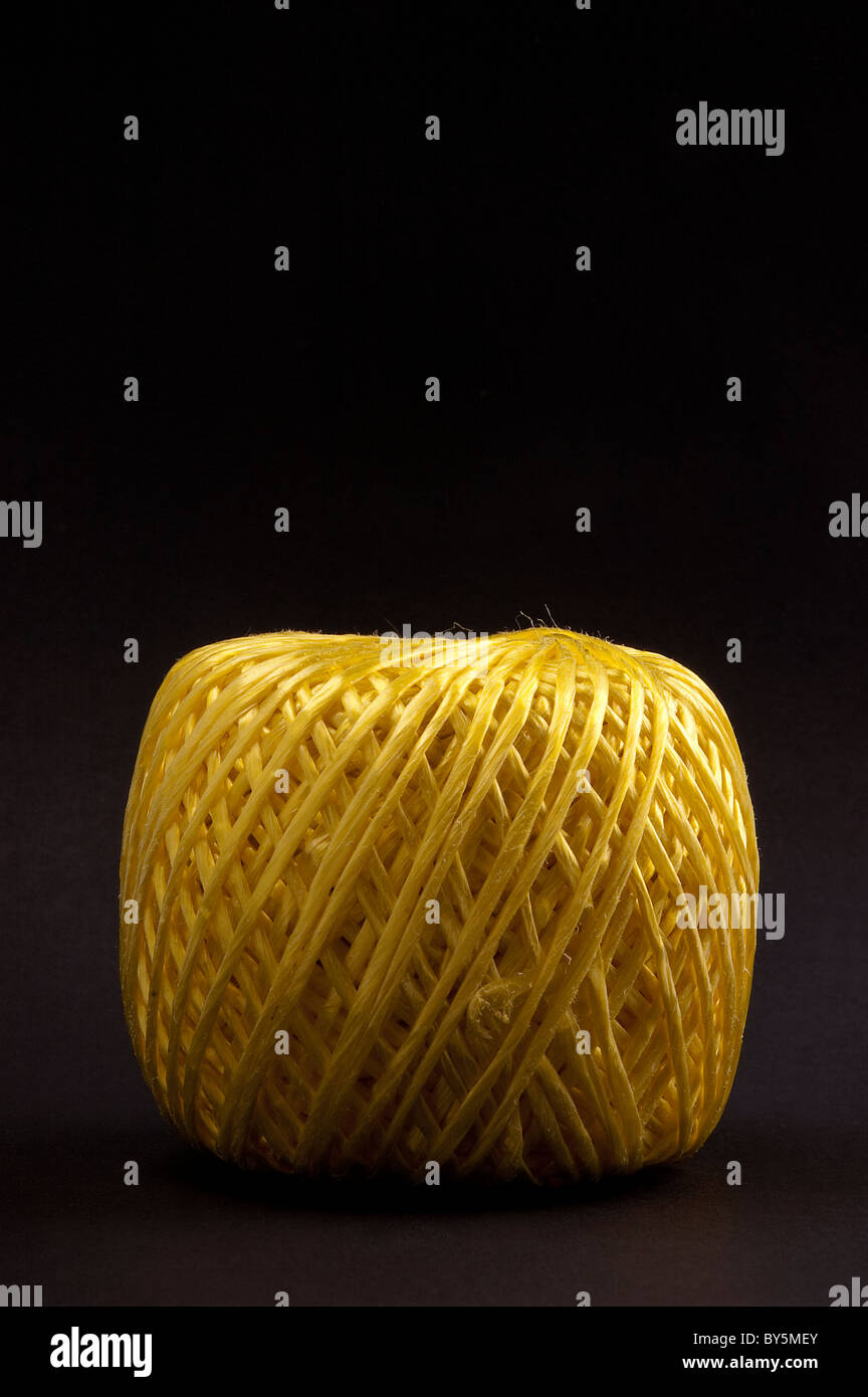 Yellow ball of string against black background Stock Photo - Alamy