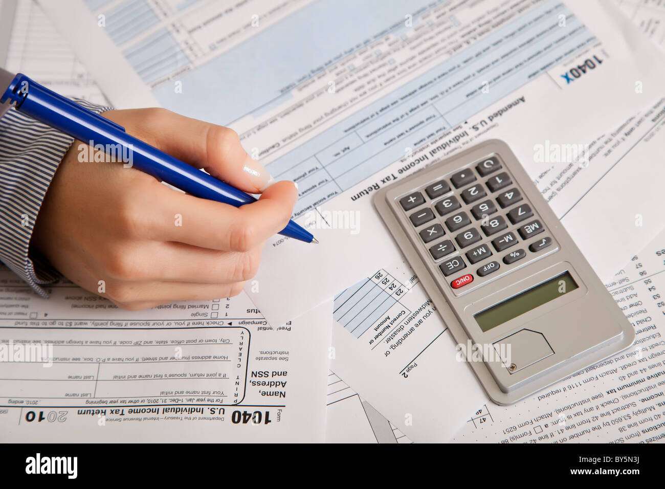 Woman hand filling income tax forms with calculator Stock Photo - Alamy