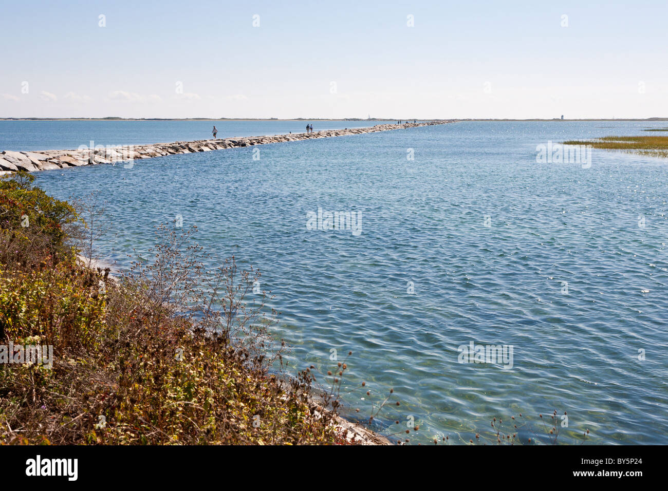 Visitors walk across west end of Provincetown Harbor on stone walkway ...