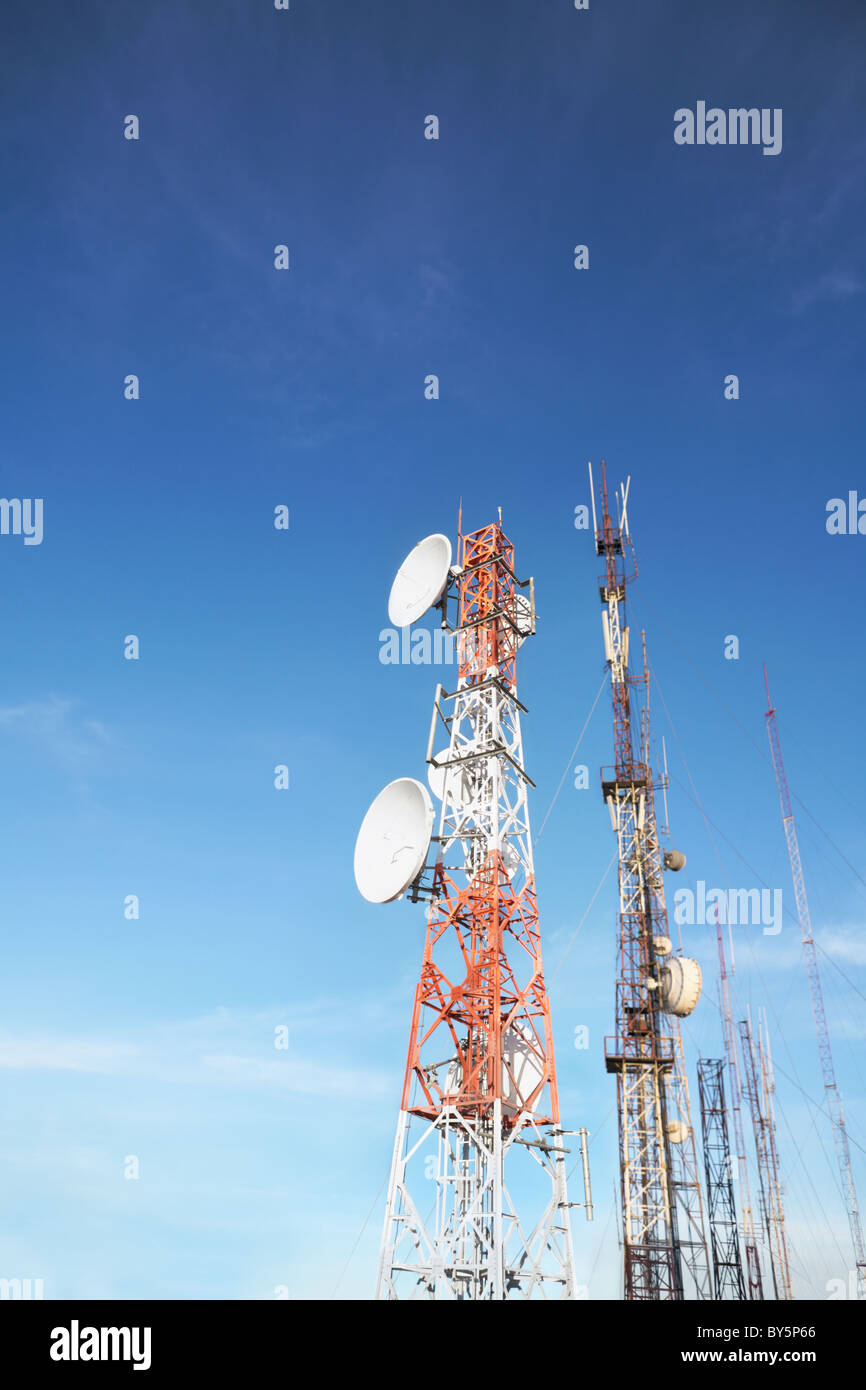 Several communication towers in the morning, against clear blue sky ...