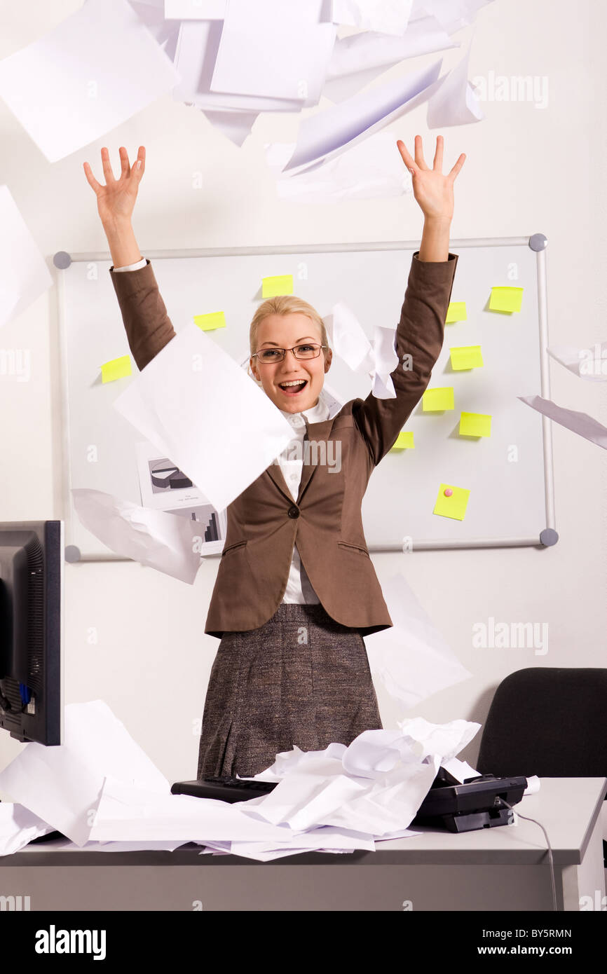 Portrait of happy businesswoman raising arms and throwing papers in ...