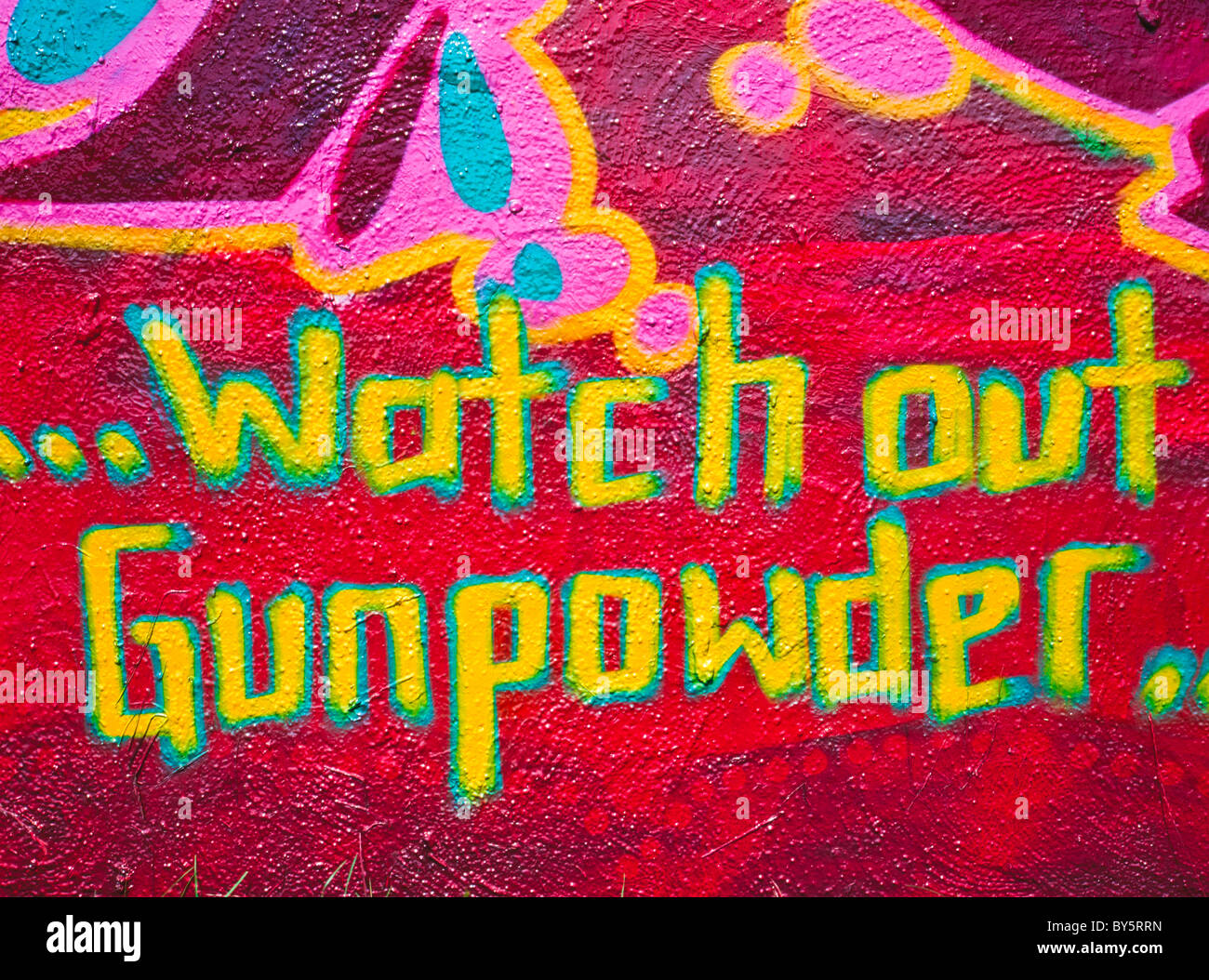 Abstract graffiti on a wall. With "watch out gun powder" written in ...