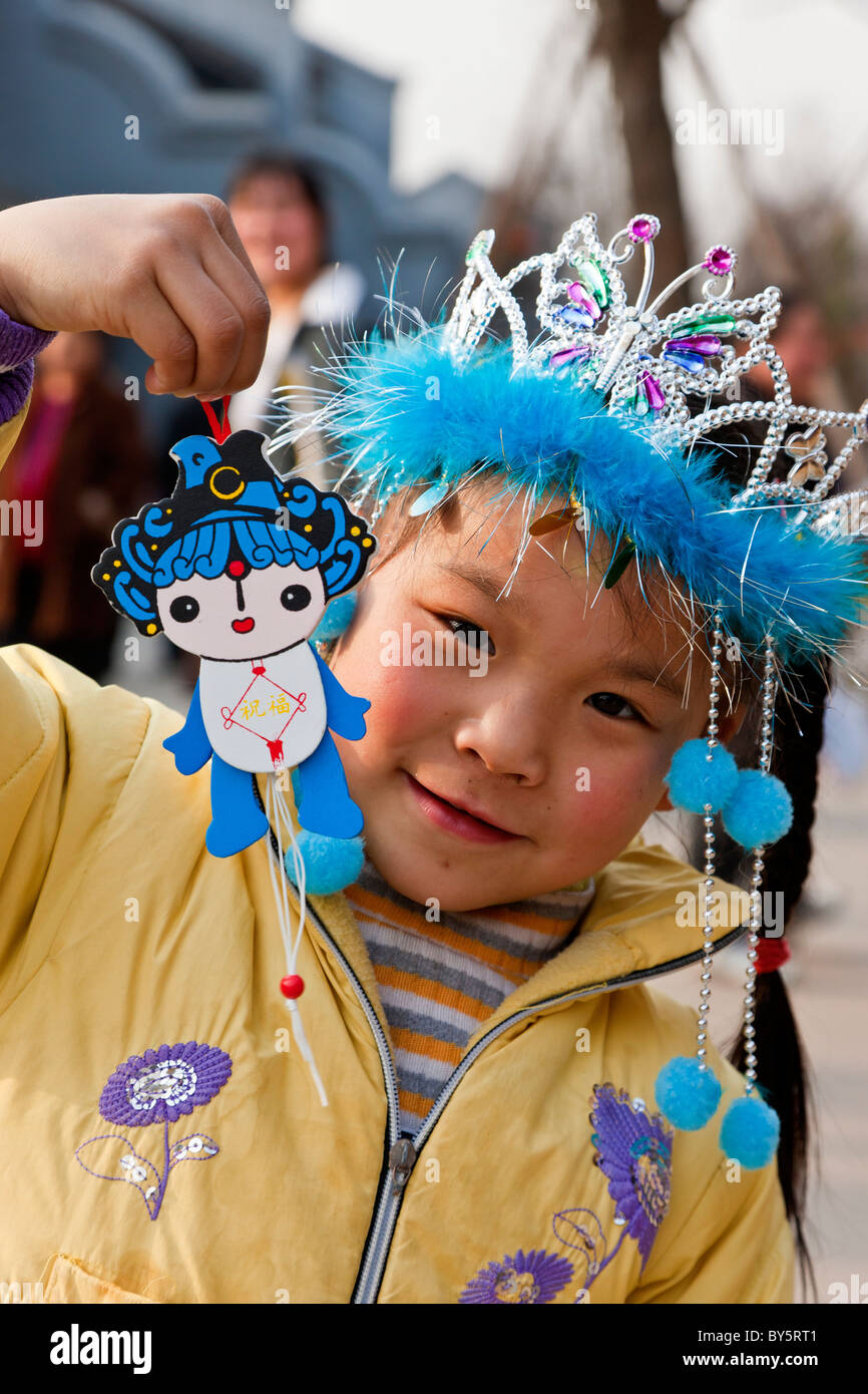 Young Chinese girl in yellow jacket and blue fur trimmed crown shows us ...