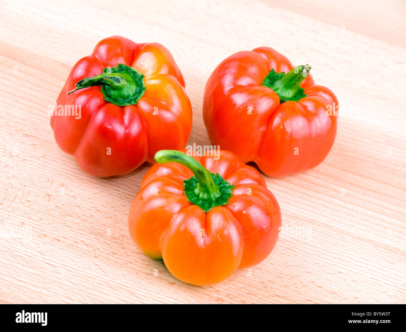 Three fresh paprikas on wooden background Stock Photo - Alamy